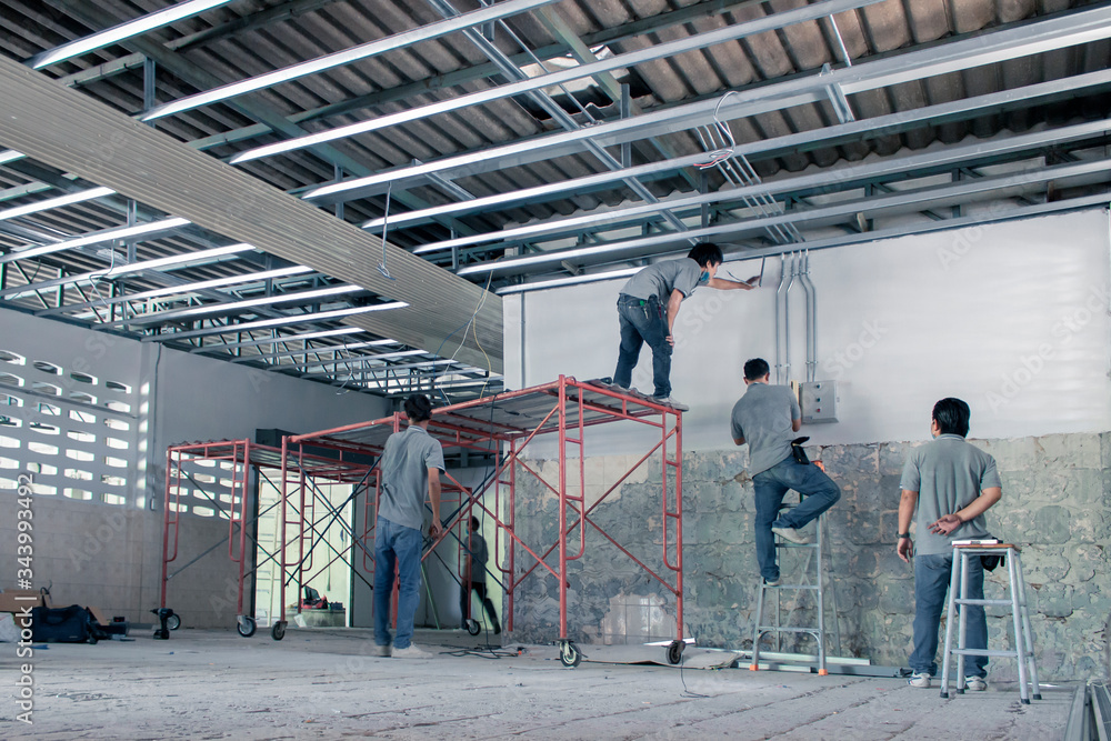 Ceiling technicians are installing electrical cables and insulation ...