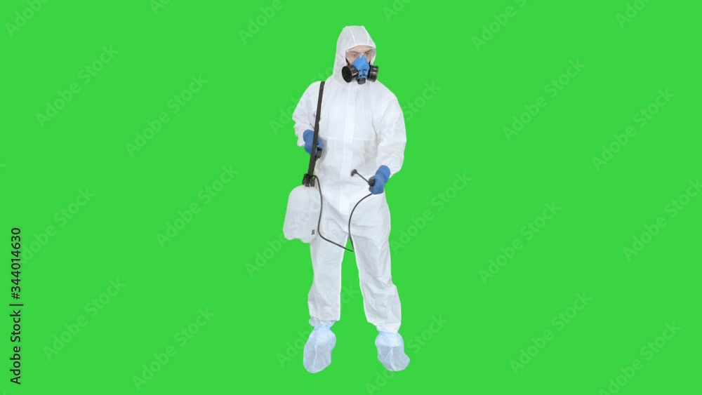 Man wearing an NBC personal protective equipment (ppe) suit spraying ...