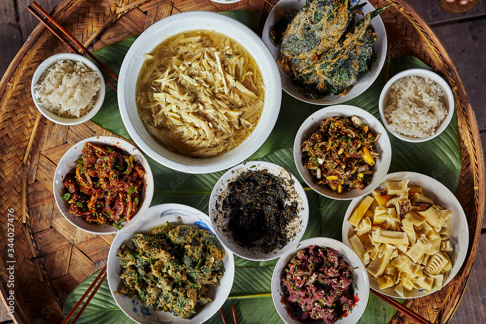scrumptious spread of Yunnan dishes on a bamboo table with 3 types of ...