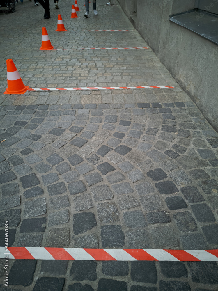 Six feet distance markings with barrier tape and traffic cones in front ...