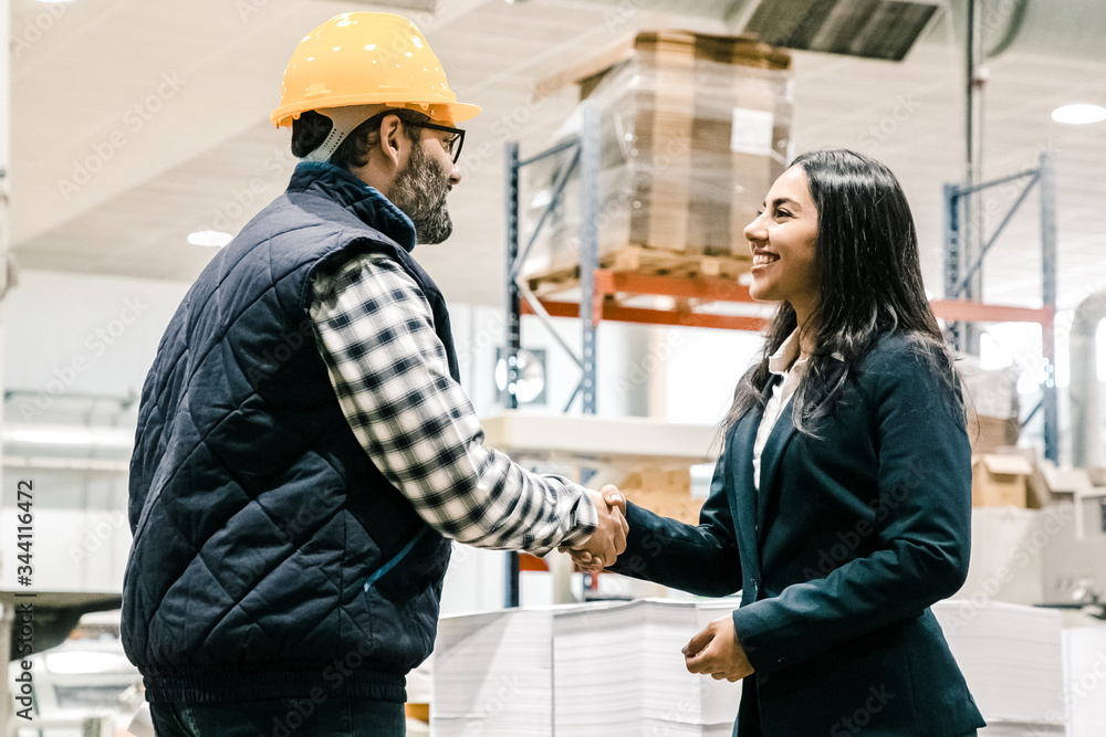 Smiling office manager shaking hands with factory worker. Cheerful ...