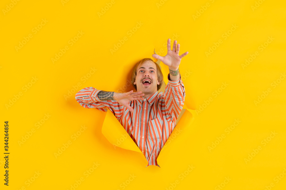 Catching something. Cheerful caucasian young man poses in torn yellow ...