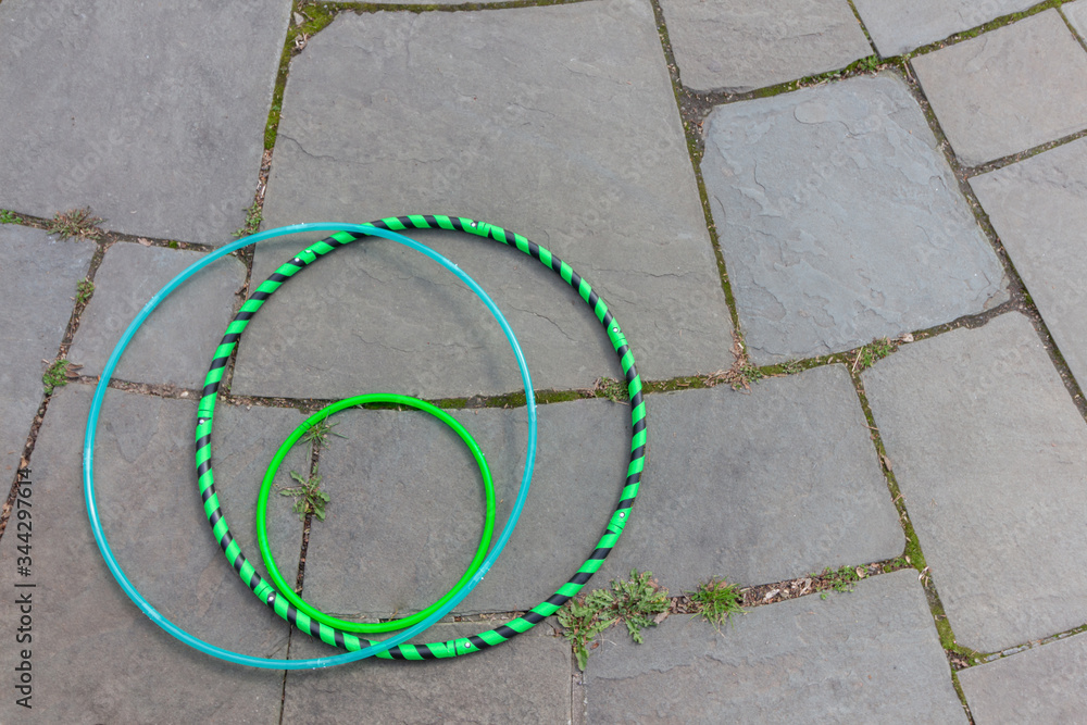 three types of exercise hoops arranged on a flagstone background. A ...