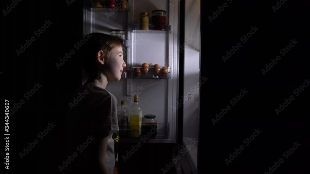 Stockvideon Shooting 4K . A young hungry boy eats at night . Hunger and ...