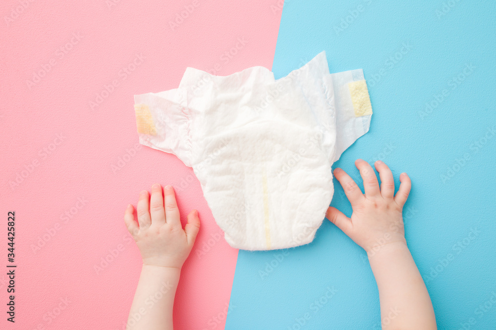 Baby hands and white diaper on light pink blue table background. Pastel ...