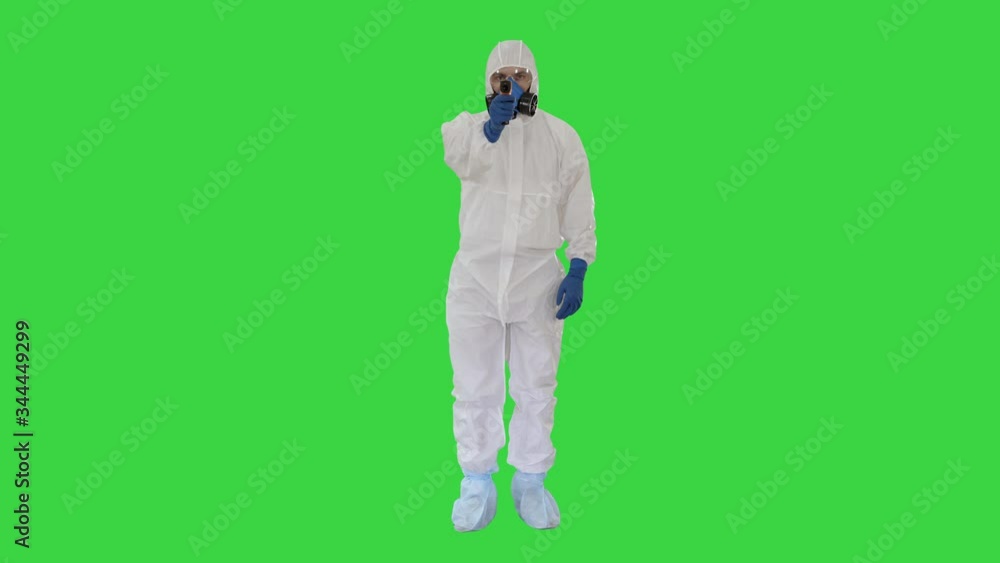 Doctor in protective biohazard suit points laser thermometer to check ...
