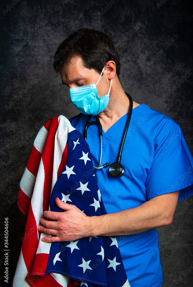 Sad/pensive male doctor in blue hospital scrubs with face mask and ...