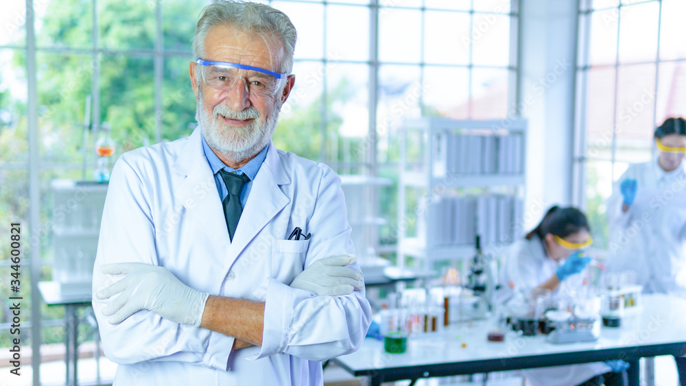 Handsome senior scientist man wearing white dress coat stand in front ...