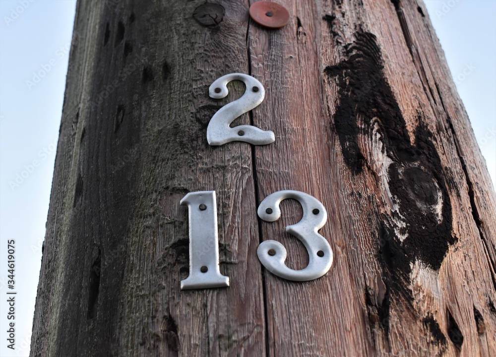 Power pole with numbers 2, 1 and 3 attached. Rough surface with tar ...