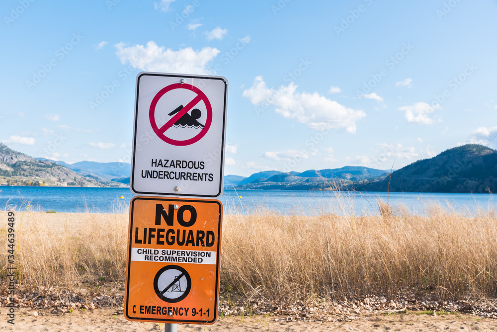 Water safety sign warning of hazardous undercurrents and no lifeguard ...