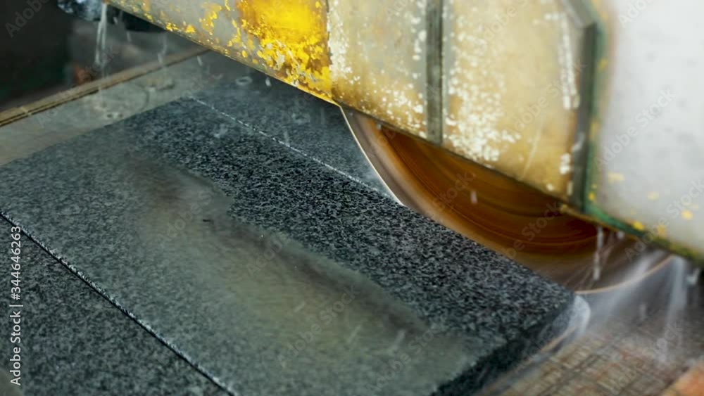 large industrial stone cutter cuts ground gray granite on tiles in ...
