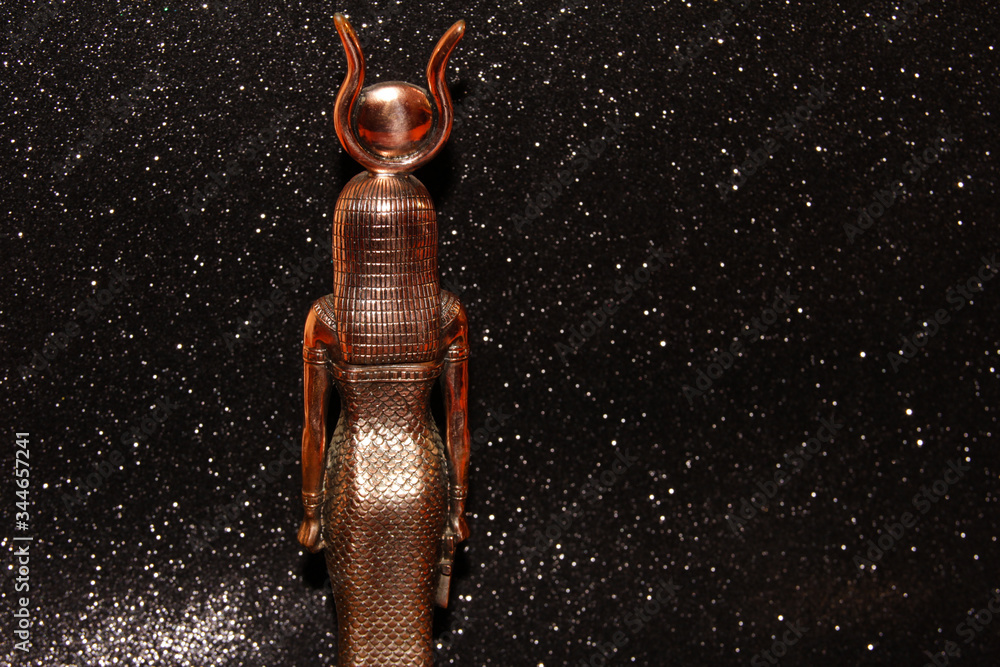 The Egyptian goddess ISIS on a black background. A bronze Egyptian ...