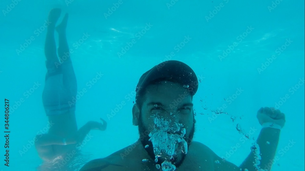 Upside Down Image Of Shirtless Male Friends Swimming In Turquoise Sea ...