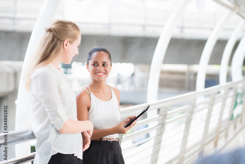Two beautiful women of different nationalities smiling and standing ...
