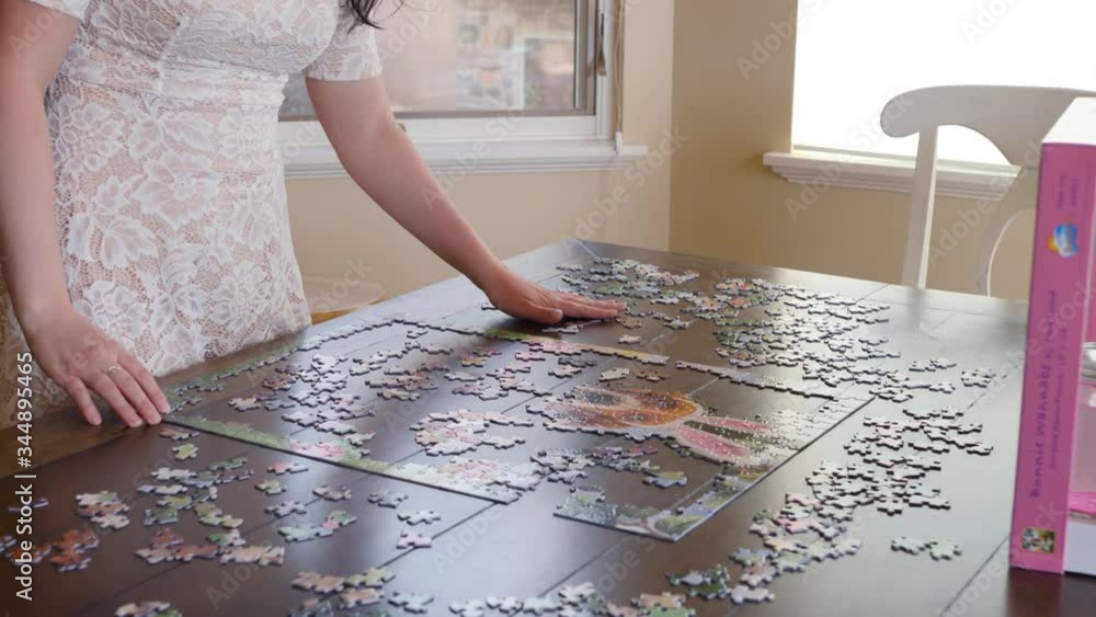 Woman Solving A Jigsaw Puzzle. Beautiful woman in the white dress is ...