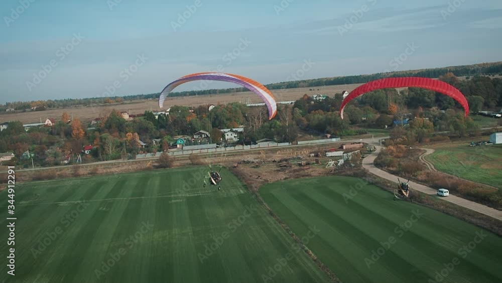 Two paratrikes fly over a rural landscape on a warm and sunny autumn ...