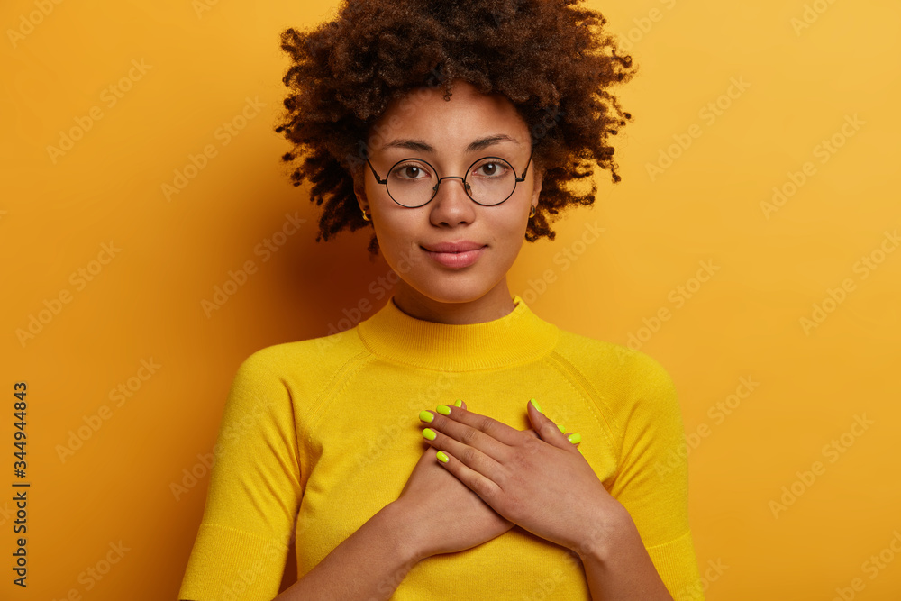 Serious calm Afro woman presses hands to heart in grateful gesture ...