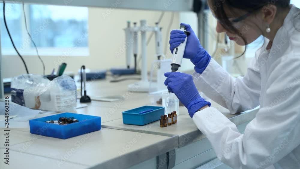 Female scientist is examining vaccine for coronavirus at table in ...