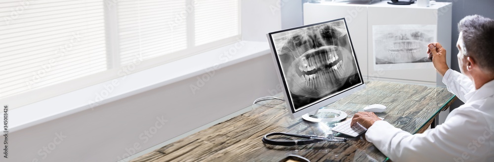 Dentist Typing On Computer With Dental X-ray On Screen Stock Photo ...