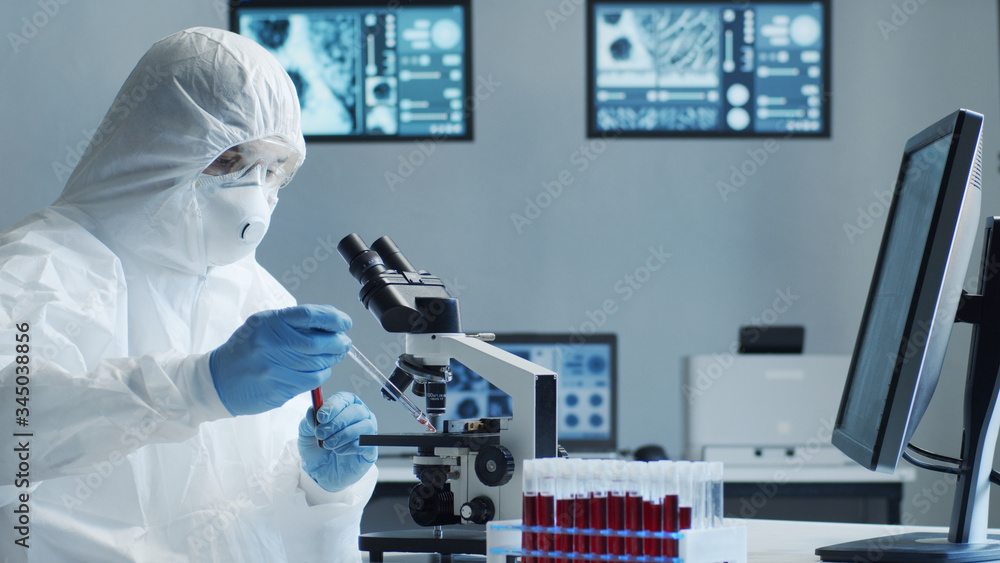 Scientist in protection suit and masks working in research lab using ...
