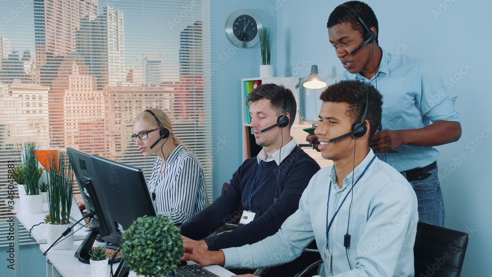 Multiethnic customer service representative telling his colleagues a ...