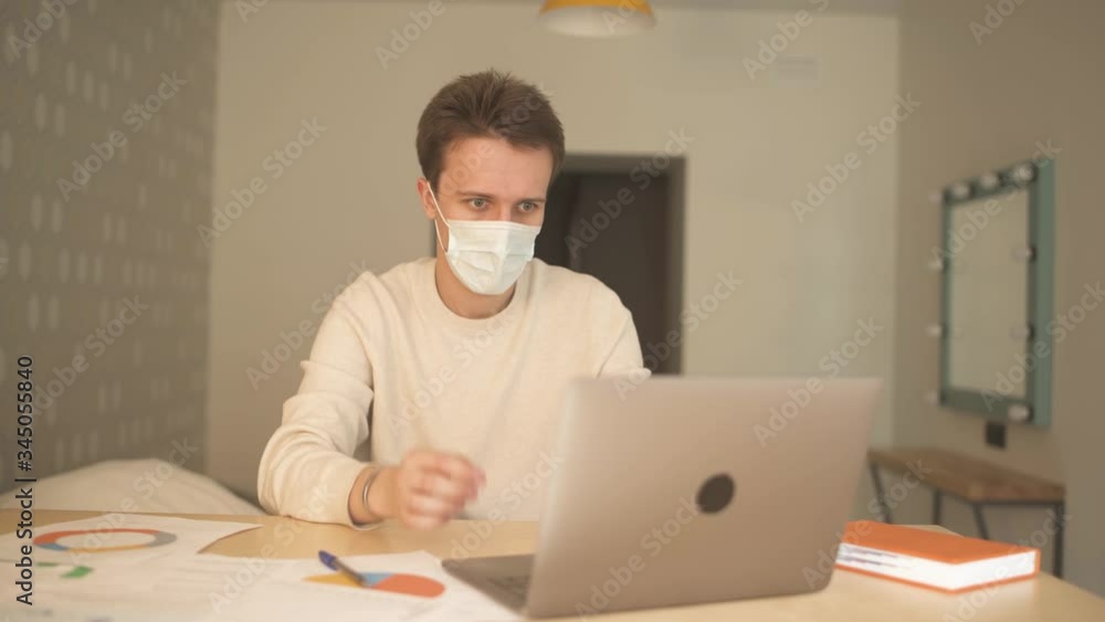 Young student in medical mask and white sweater doing an exam test and ...