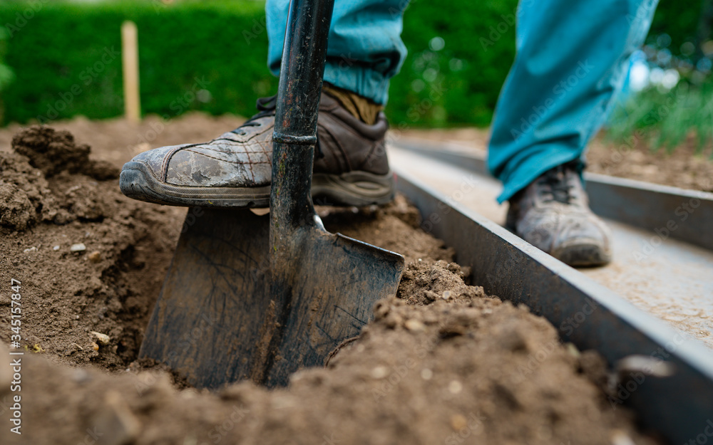 Male foot wearing a rubber boot digging an earth in the garden with an ...
