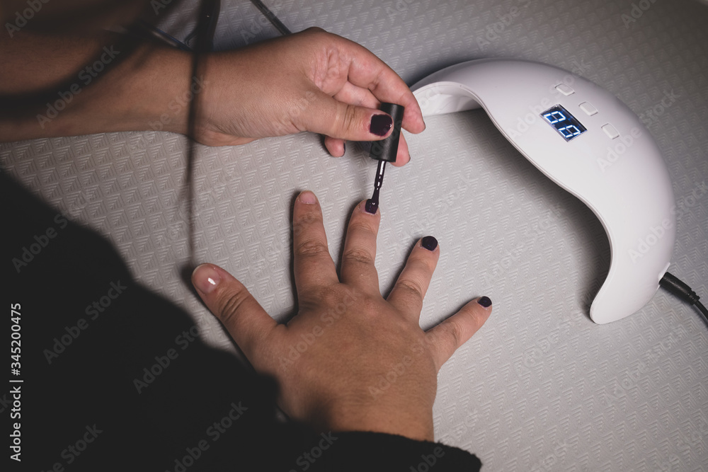 Female hands apply shellac during manicure procedure, flat lay. Woman ...