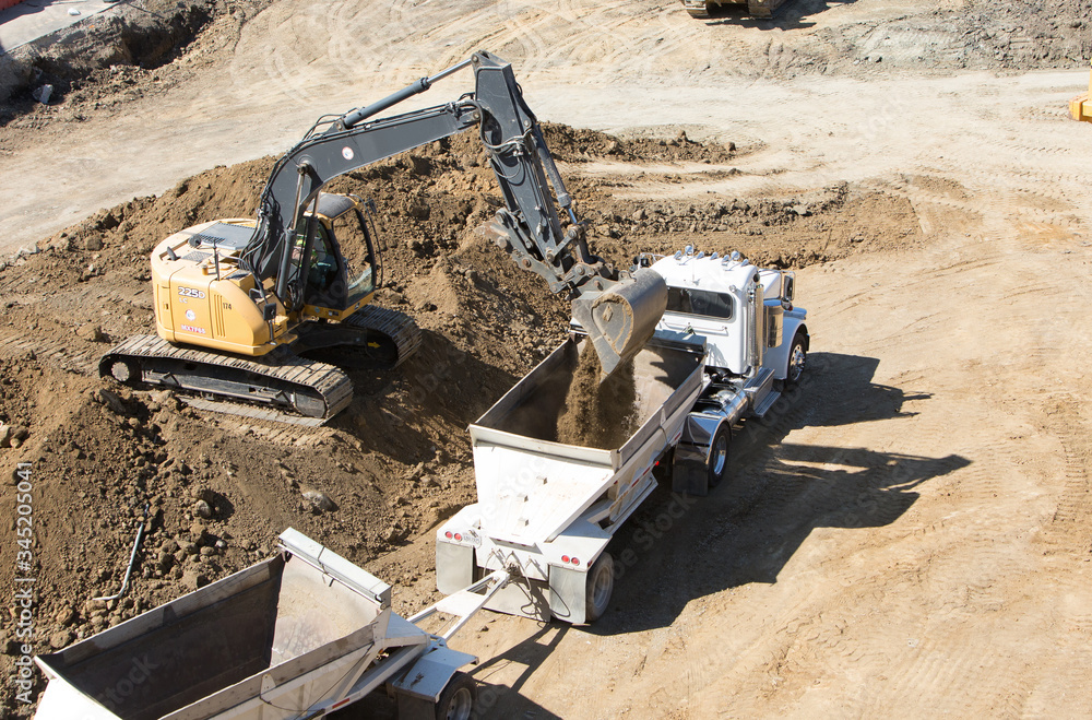 Construction site with excavator loading soil into dirt hauler truck ...