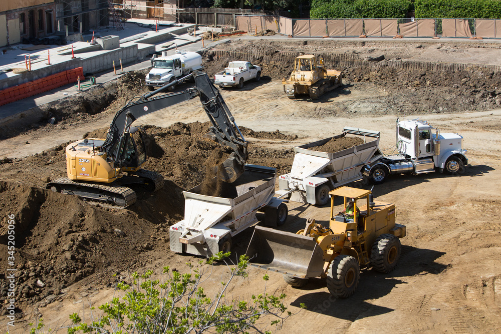 Excavator loading dirt into dirt hauling truck trailer with loader in ...