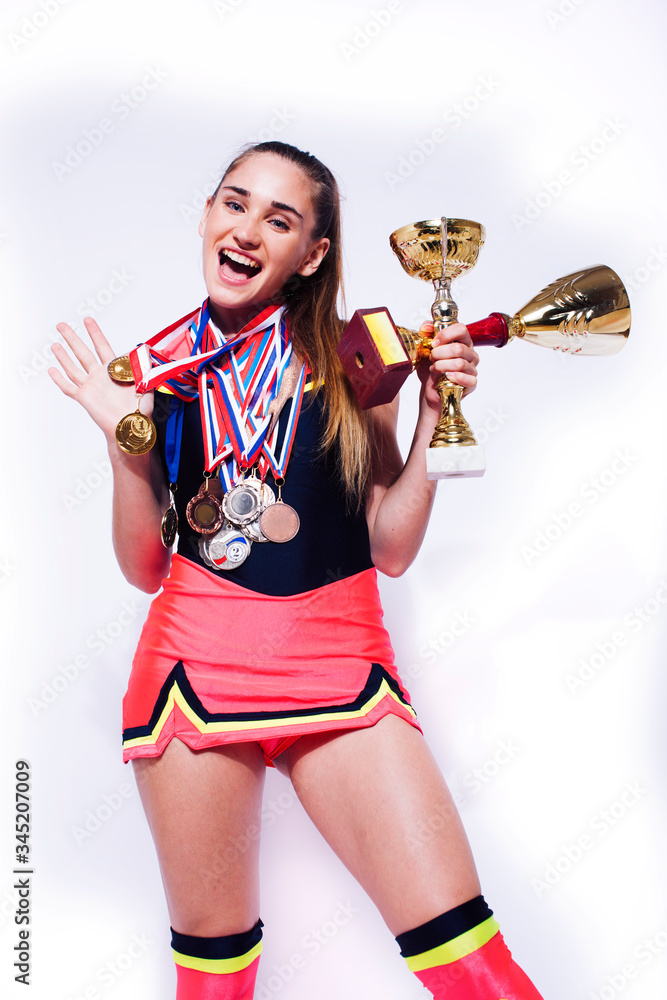 young smiling cheerleader girl with golden cups and price medals ...