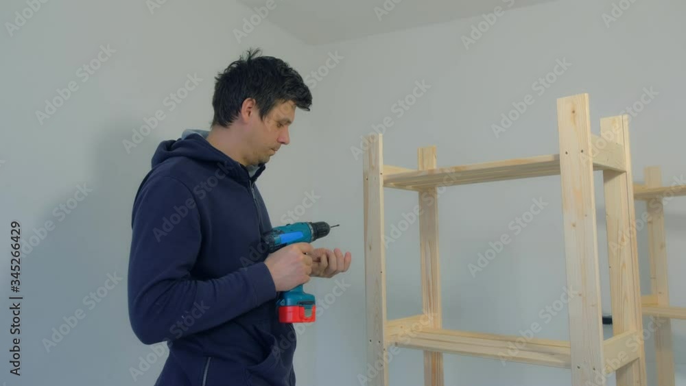 Portrait of man screwing parts with bolts using electric screwdriver ...