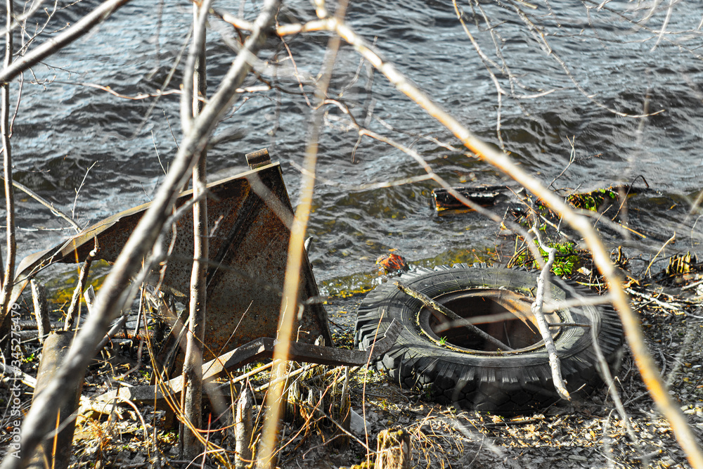 car wheels and other scrap metal washed ashore. pollution of nature by ...
