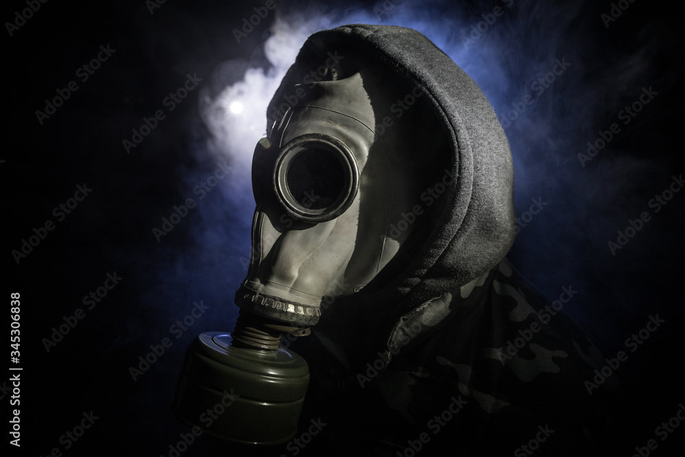 Gas mask with clouds of smoke on a dark background. Sign of radioactive ...