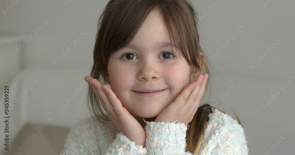 Adorable little girl looking at camera with hans on her cheeks. Smiling ...