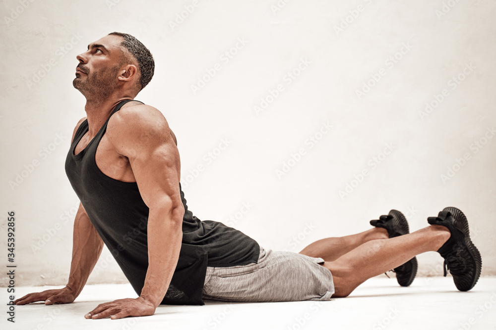 Strong and muscular athlete posing in a bright studio while doing a ...