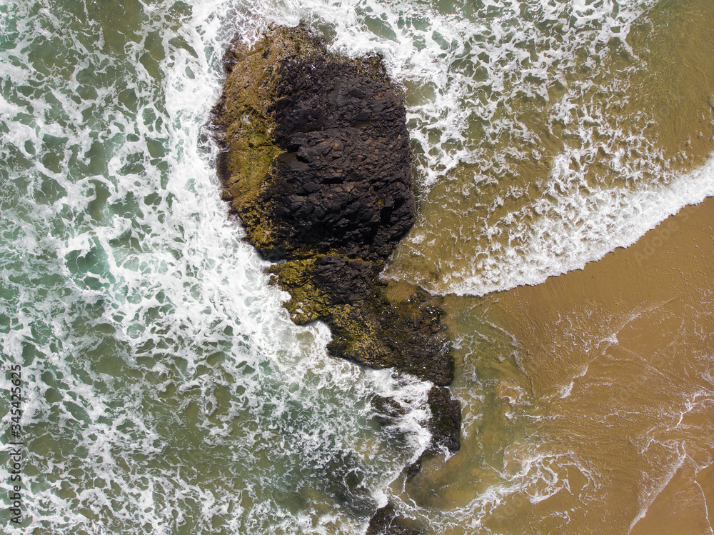 Rock in the ocean, with a beach and sand. Top view, waves, natural ...