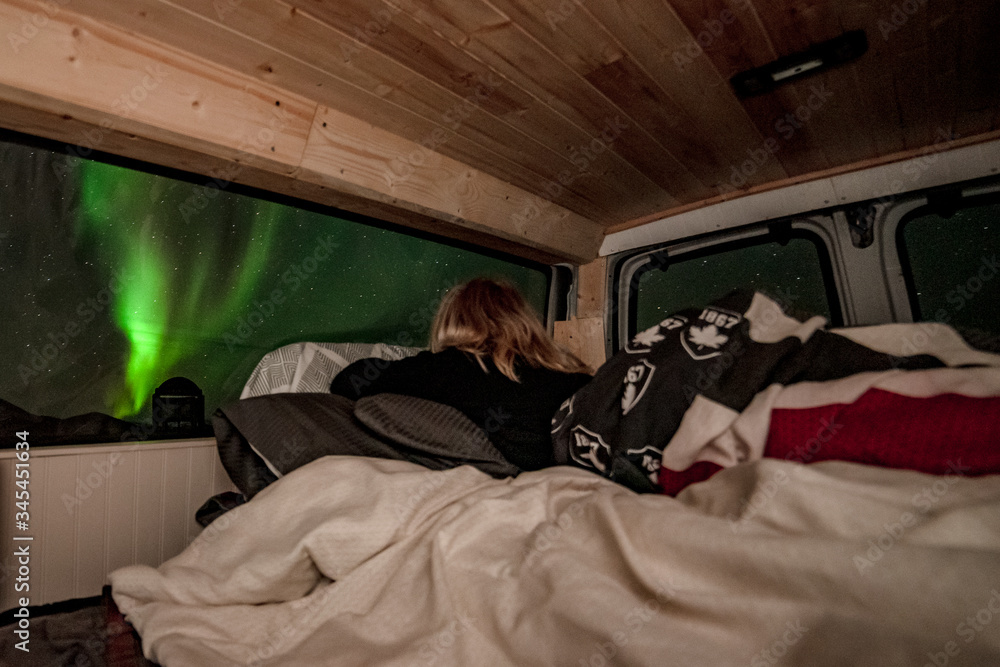 Poster Woman laying in van life, camper van bed watching aurora ...