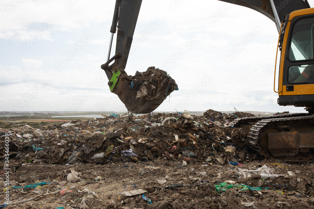 Foto de Rubbish piled on a landfill full of trash and a digger collects ...