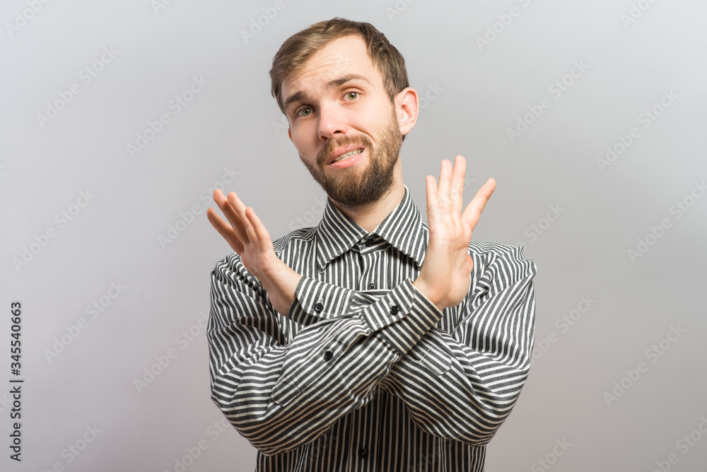 Serious and determined young man makes an X shape with his arms and ...