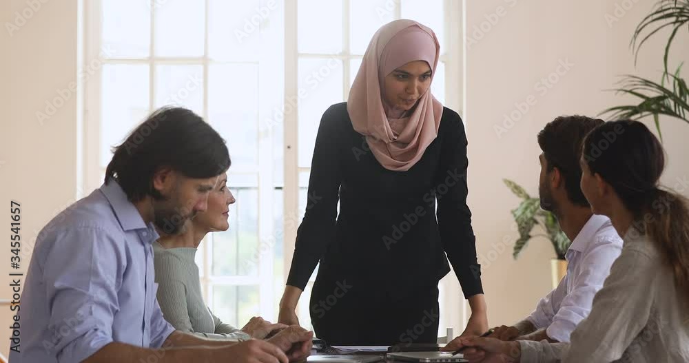 Pleasant young asian islamic female team leader in hijab standing at ...