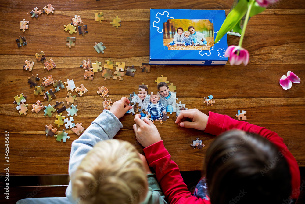 Two children, boys, assembling puzzle with their picture from an autumn ...