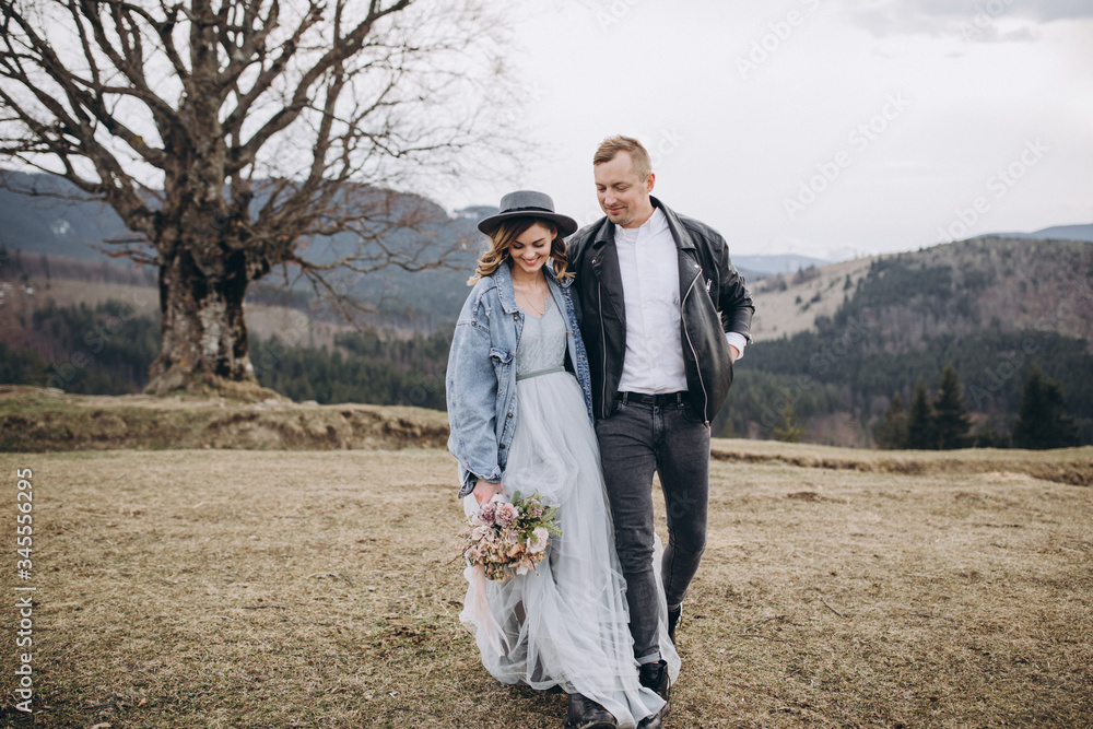 Stylish couple in the mountains. A guy in a leather jacket and a young ...