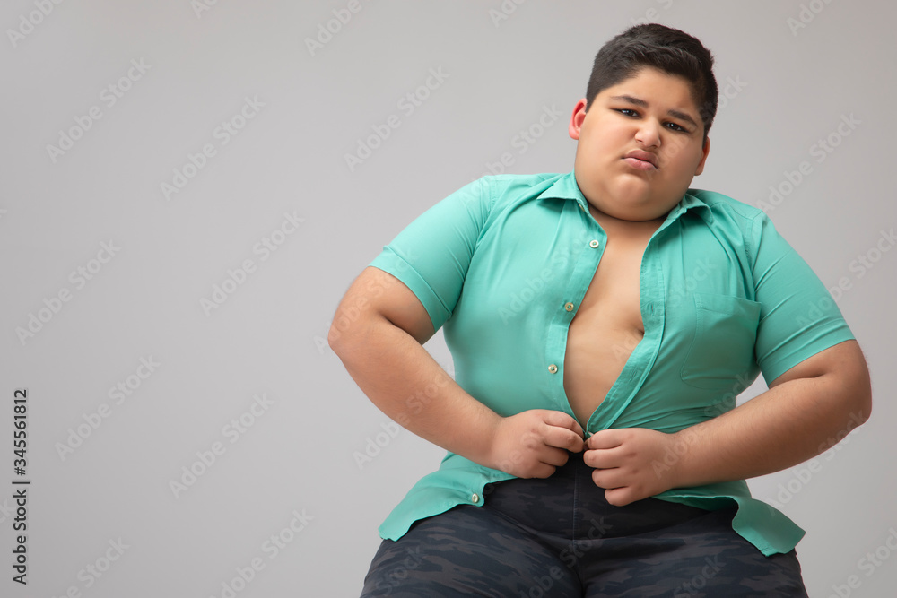 Young boy struggling to fit in a tight shirt. (Obesity) Stock Photo ...