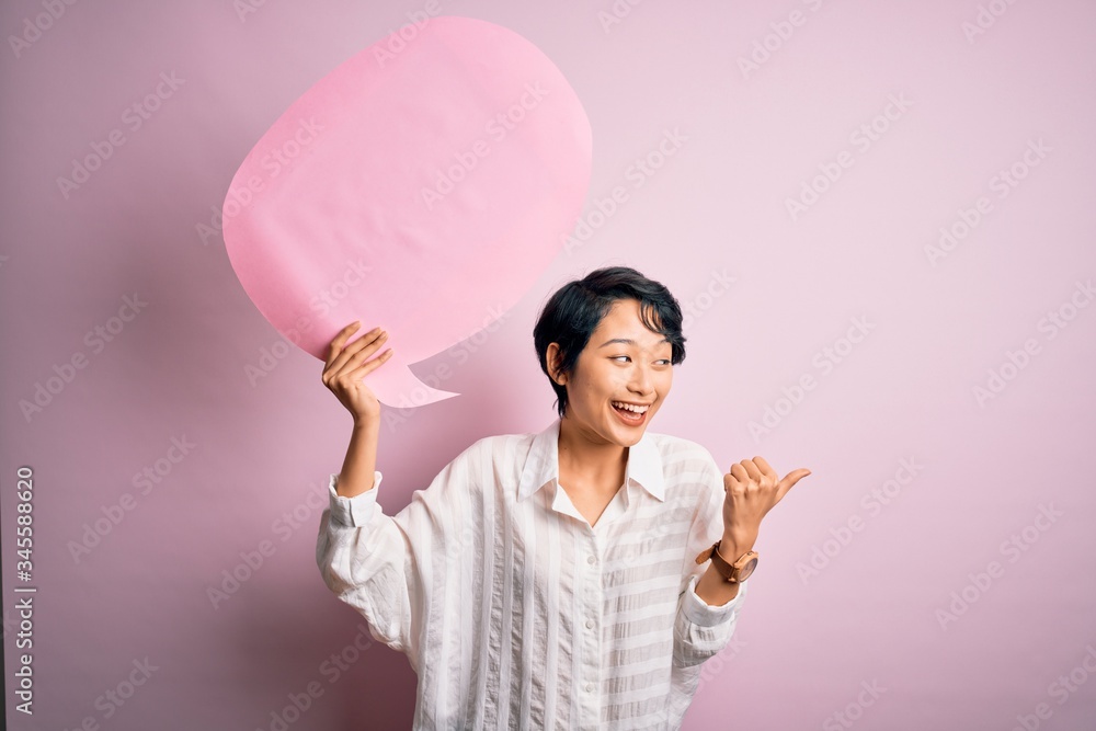 Young beautiful asian girl talking holding speech bubble over isolated ...