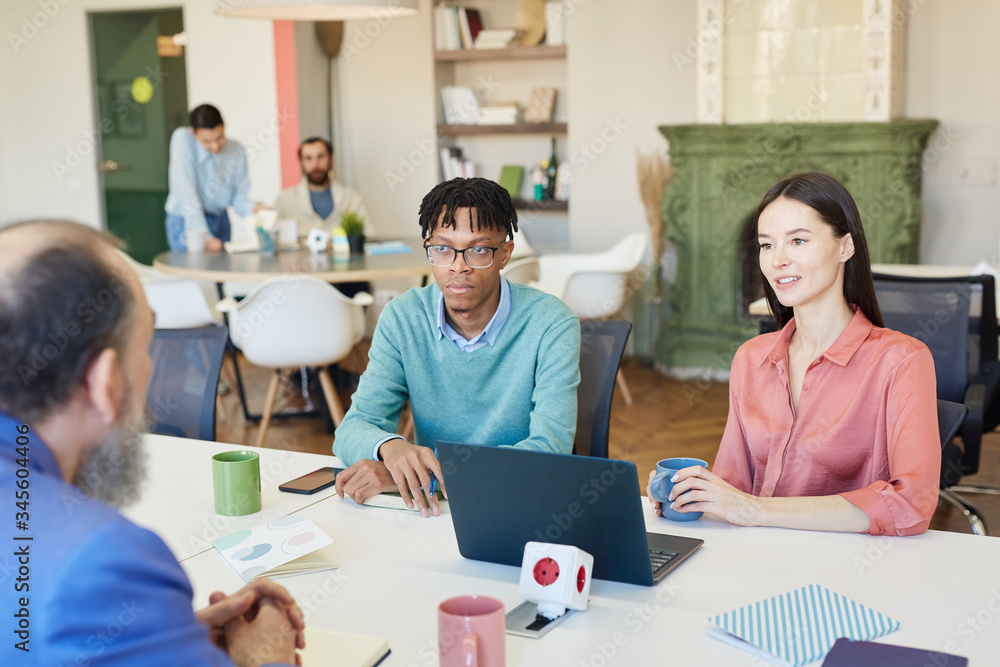 Group of modern business people sitting together at office desk working ...