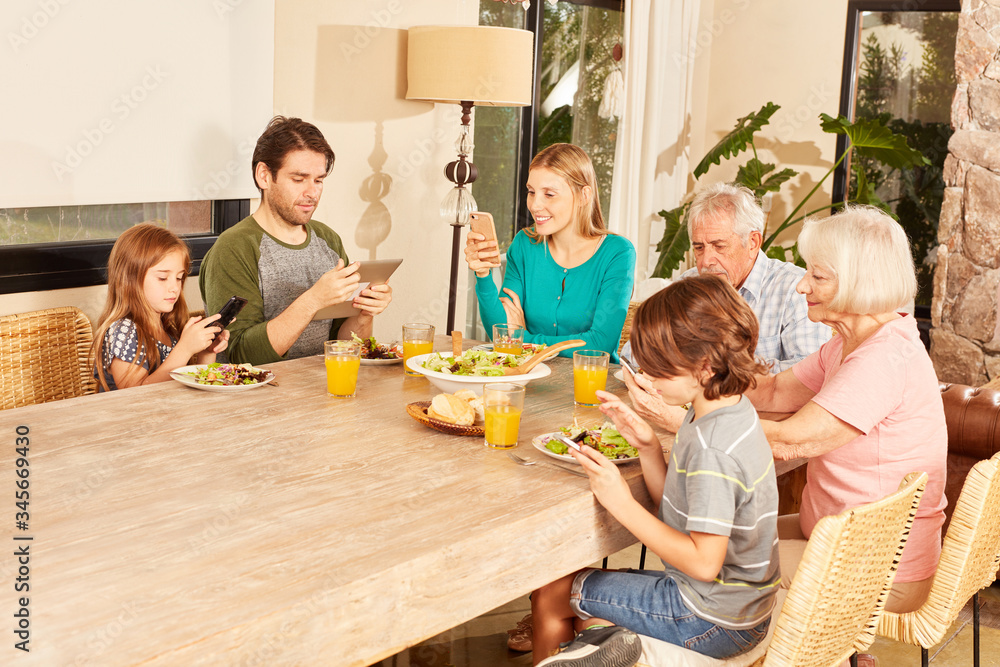 Family at the dining table with tablet and smartphones Stock Photo ...