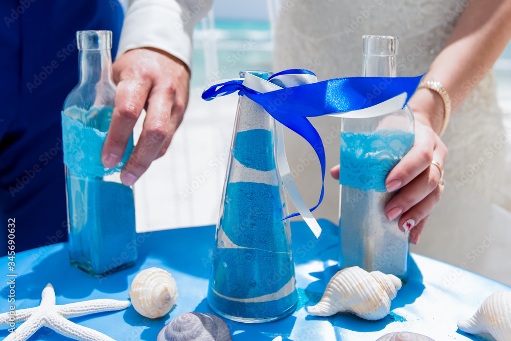 Bride and groom pouring colorful different colored sands into the ...