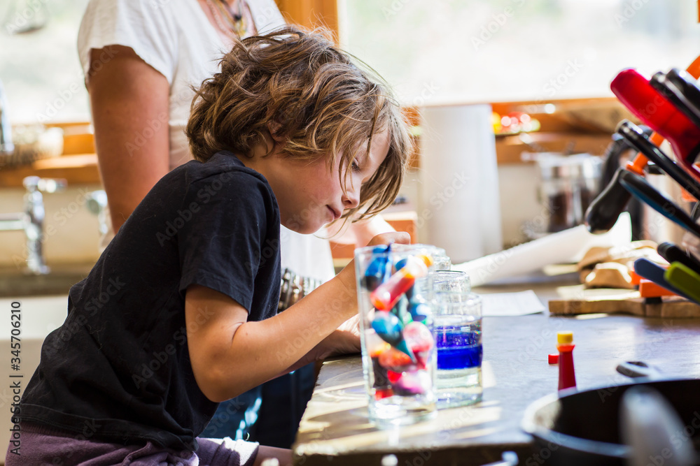 6 year old boy in kitchen with his mother, doing science experiment ...