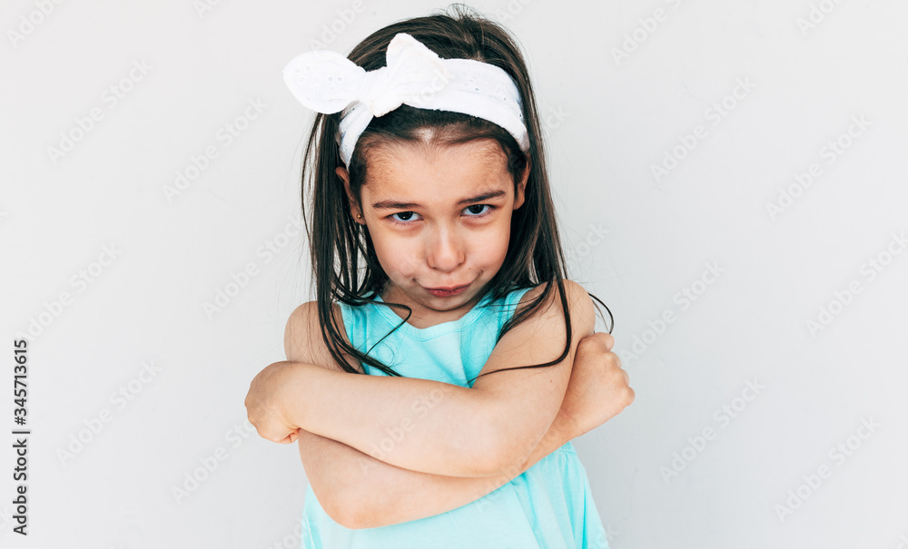 Portrait of the angry little girl wearing blue dress and white bow with ...